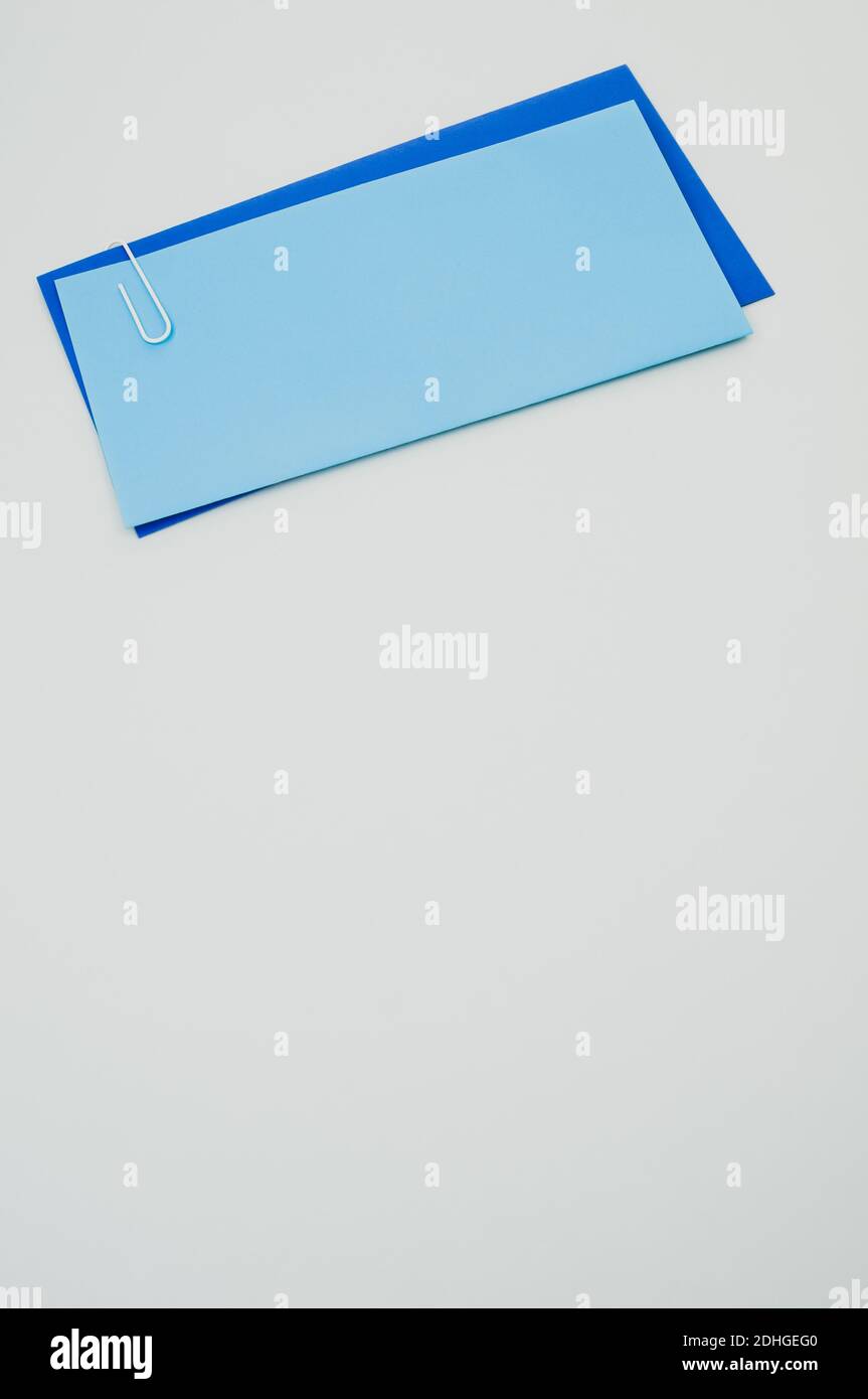 A vertical shot of pieces of paper attached with a paper clip on a gray ...