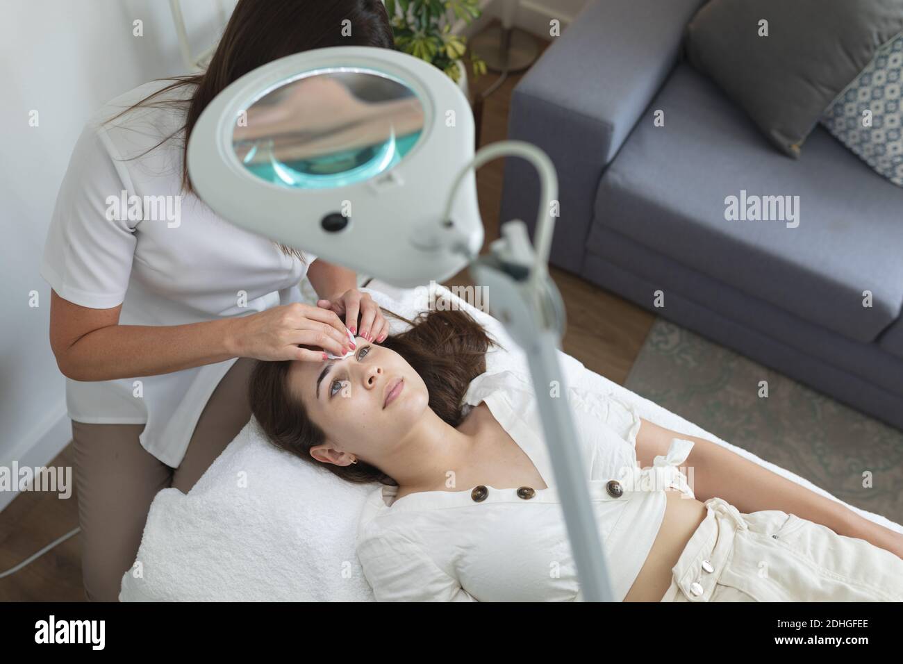 Caucasian Woman Lying Back While Beautician Wipes Her Eyebrows Stock