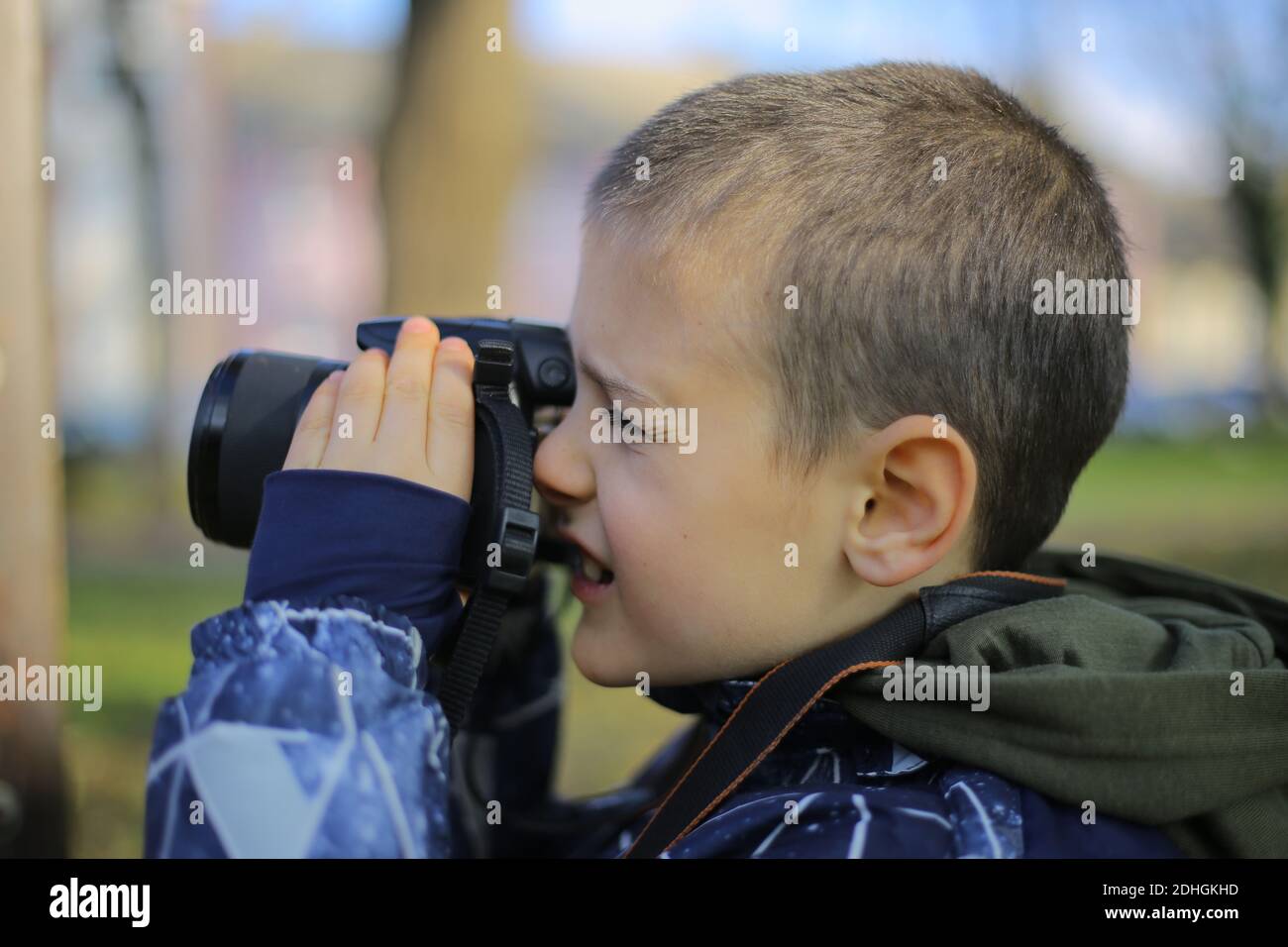 A shallow focus of a kid taking pictures with a DSLR camera outdoors ...