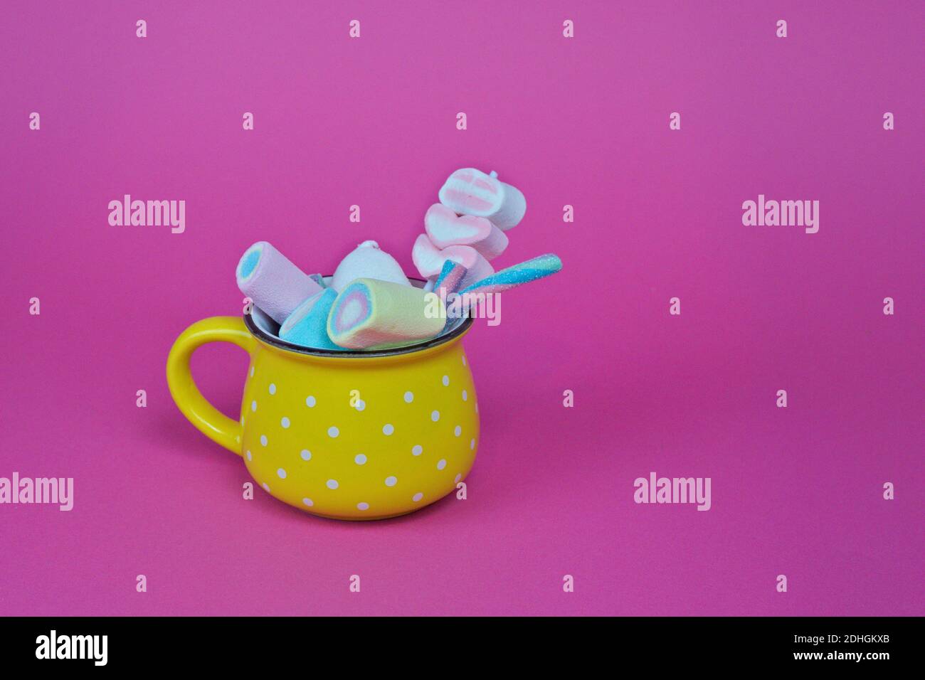 A closeup of sweets and snacks in a yellow mug with polka dots isolated ...