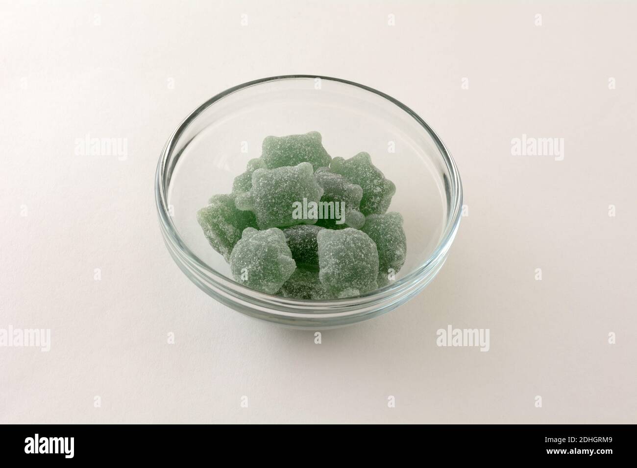 Sour green gummy candy in shape of turtle in glass snack bowl on white ...