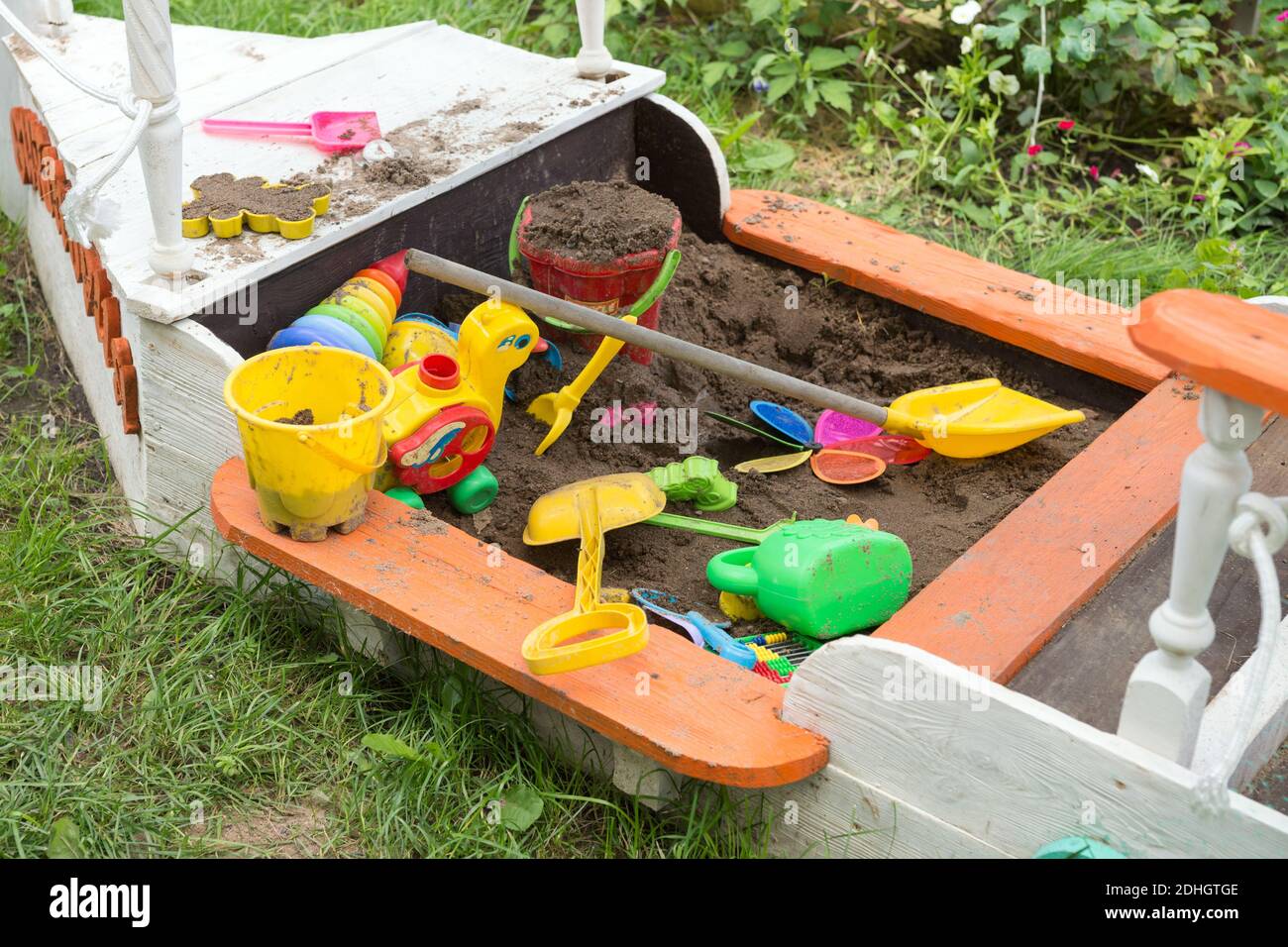 Children's sandpit in the form of a boat with scattered bright toys ...