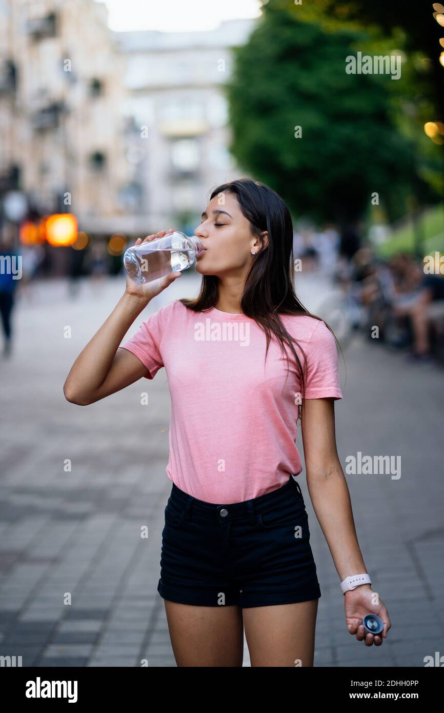 Beautiful young girl drinks with a bottle of water Stock Photo - Alamy