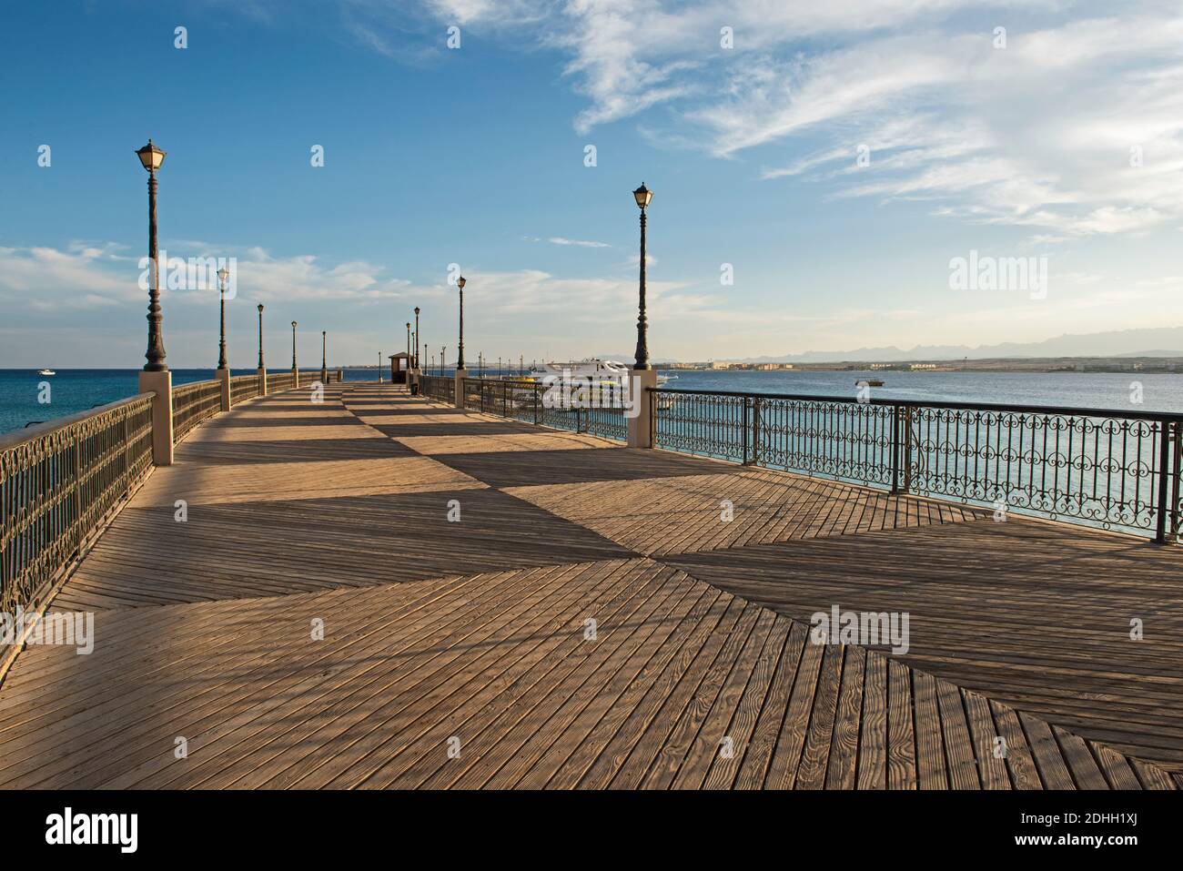 Scenic view down a large wooden jetty pier over sea in tropical coastal ...