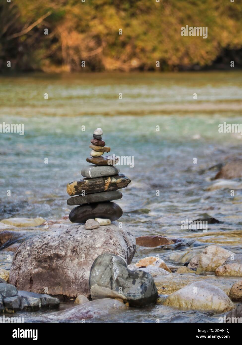 A vertical shot of a tower made with rocks and stones by the river ...