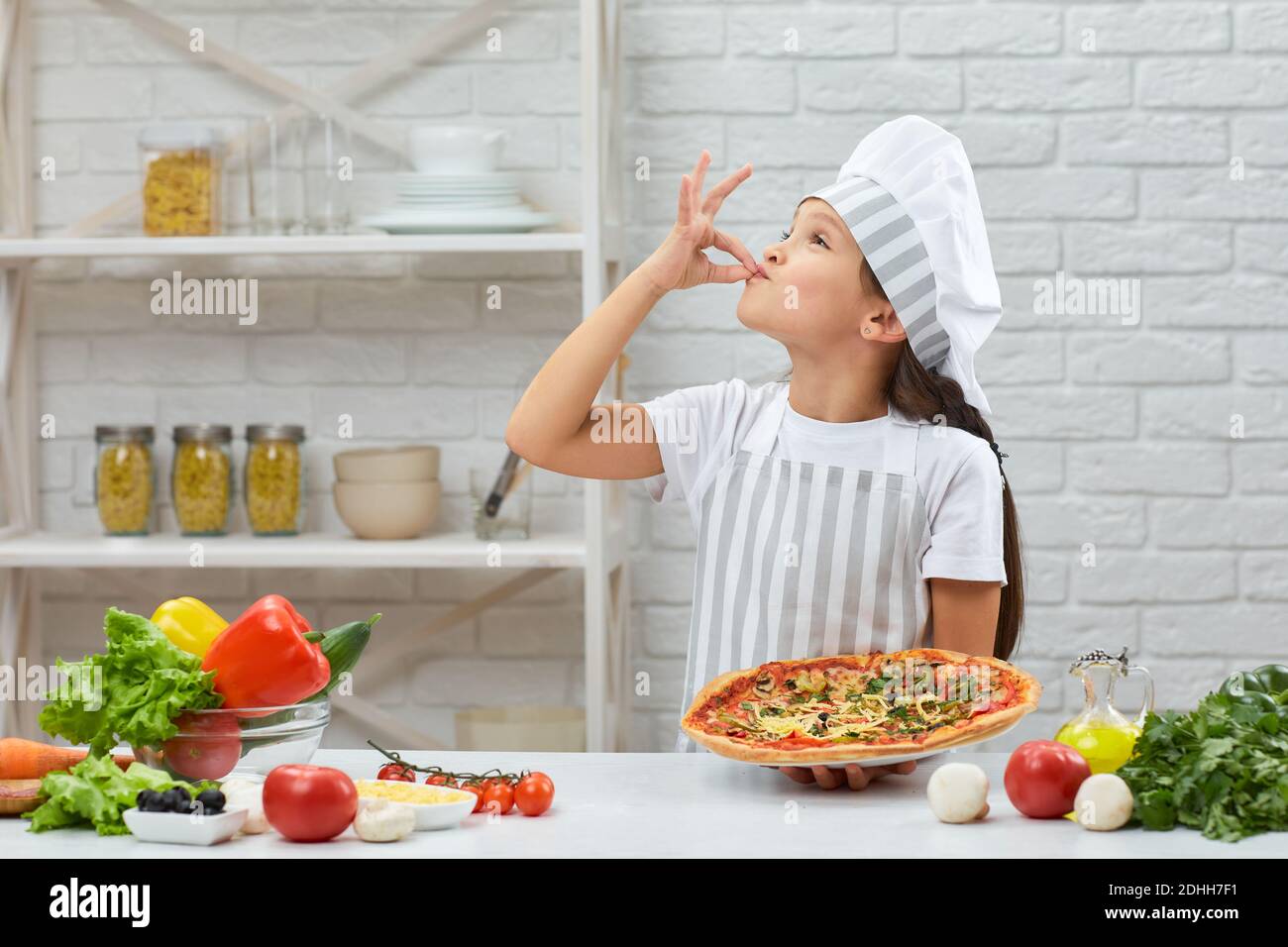 child making tasty delicious gesture by kissing fingers. little girl in ...