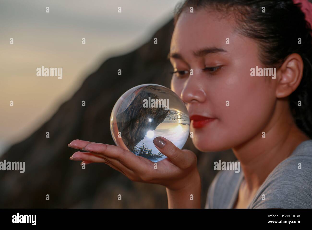 A lady hold a crystal ball to view of sunset inside crystal ball Stock ...