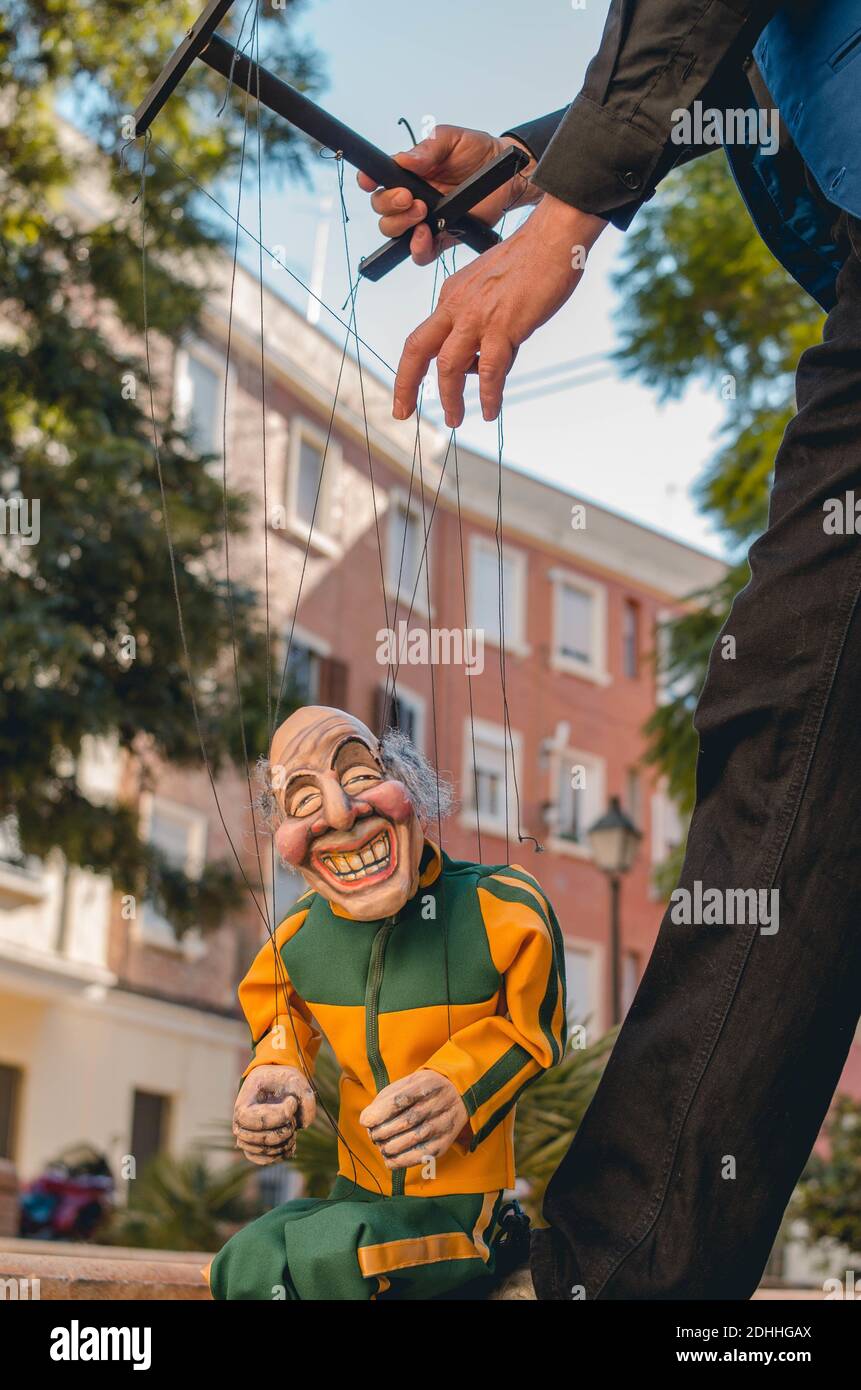 A vertical shot of a male holding an old smiling puppet in tracksuit ...