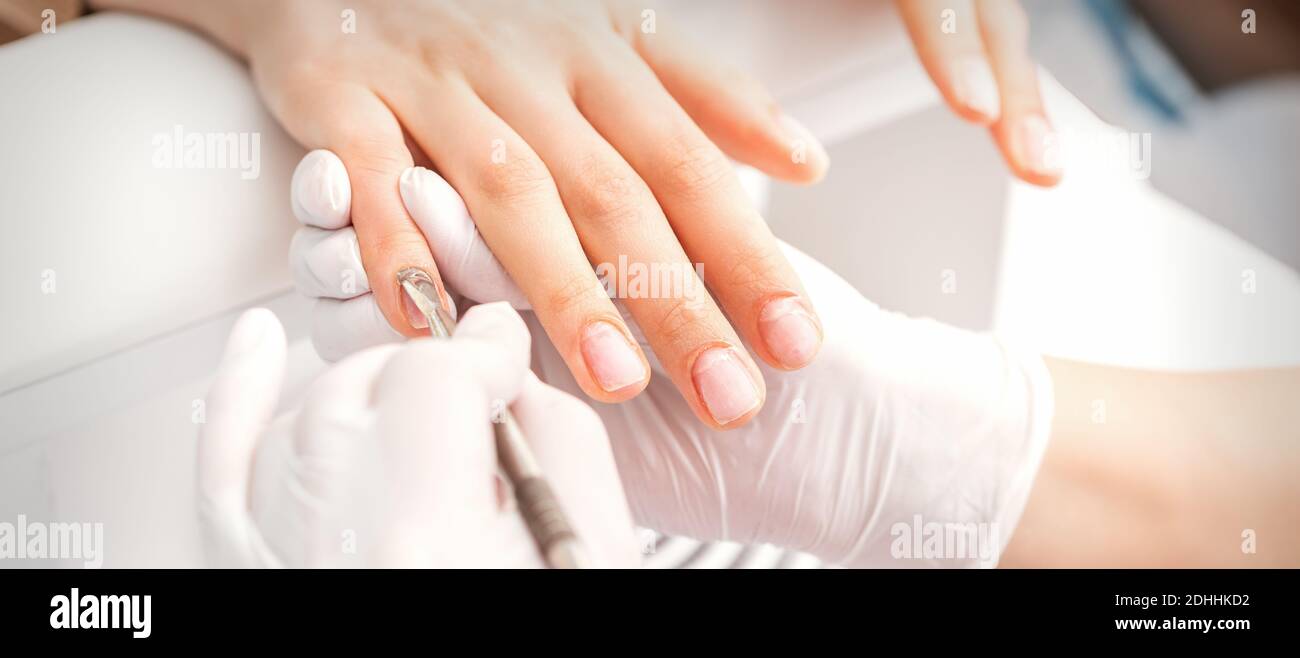 Closeup of beautiful woman's fingernails receiving cleaning cuticle ...
