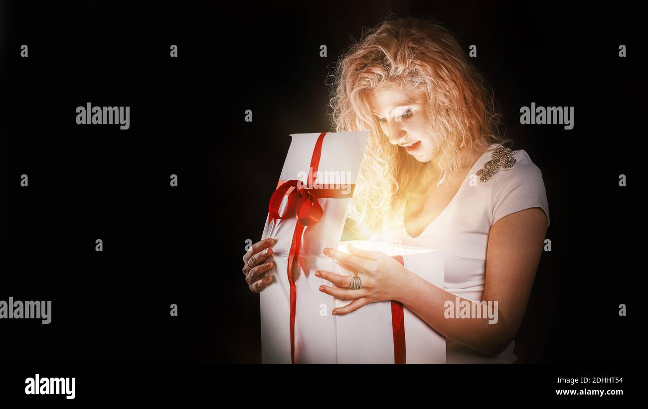 beautiful young woman opening gift box . isolated on black Stock Photo ...