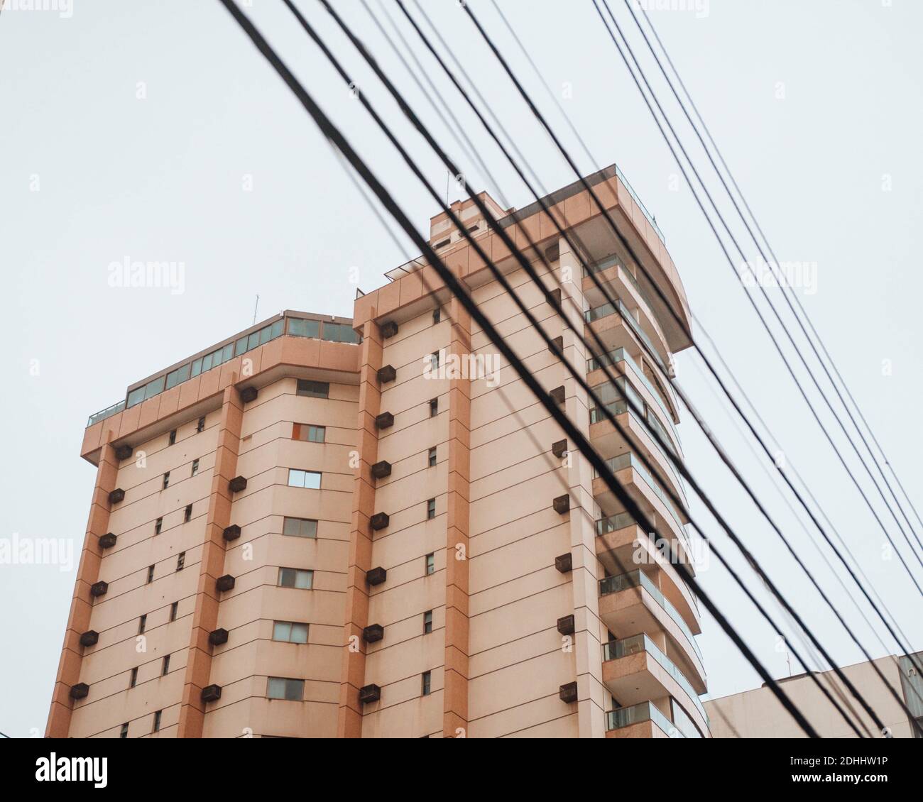 A low angle shot of a condominium building seen behind the power cables ...