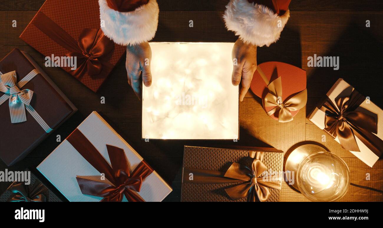 Santa Claus opening a precious Christmas gift on his desktop, there is ...