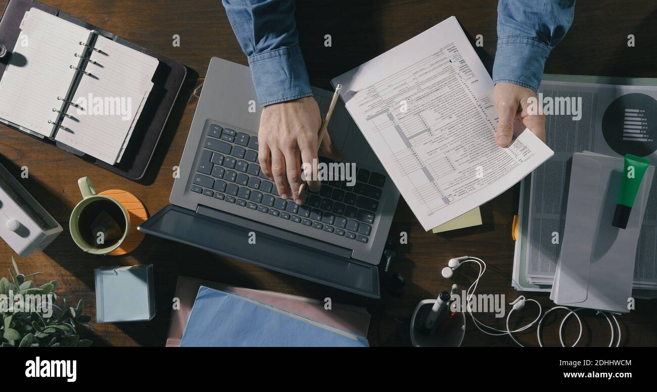 Businessman sitting at office desk and working, he is checking ...