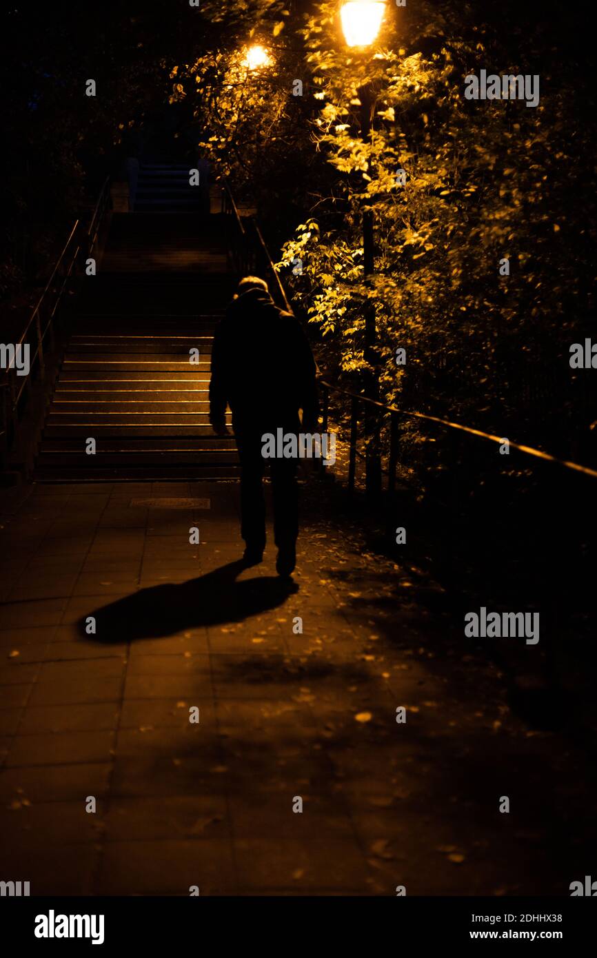 A vertical shot of a male going stairs up at night Stock Photo - Alamy