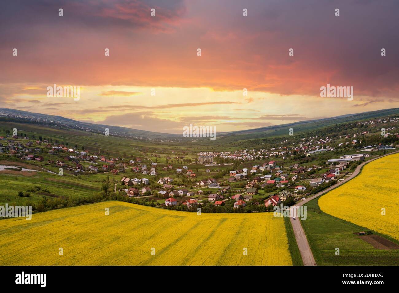 Aerial view of ground road with moving cars in green fields with ...
