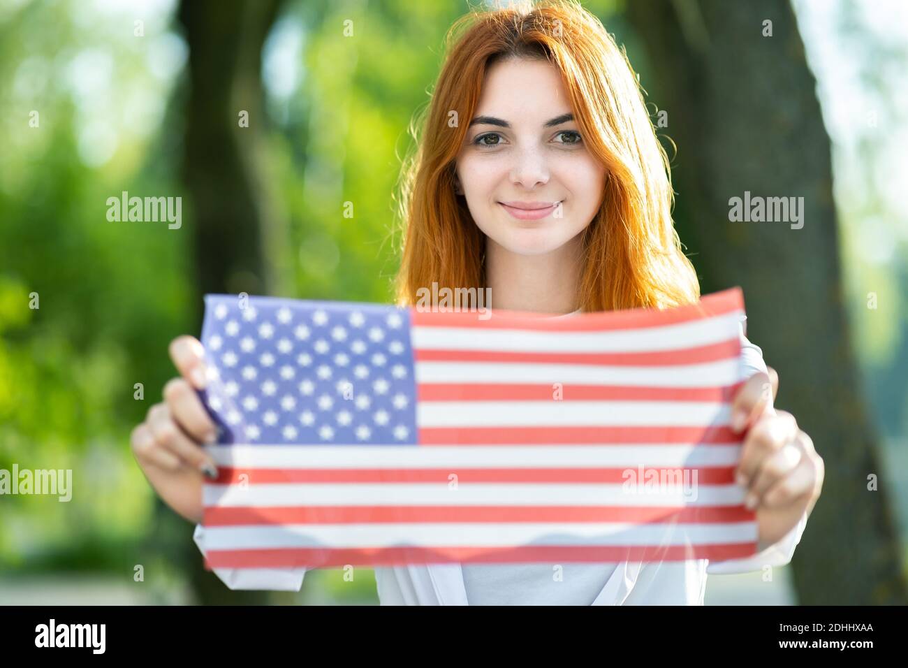 Happy young woman posing with USA national flag holding it in her ...