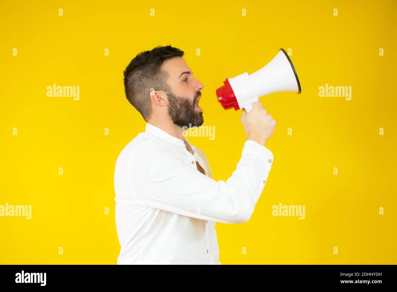 Man yelling into a megaphone over yellow background Stock Photo - Alamy
