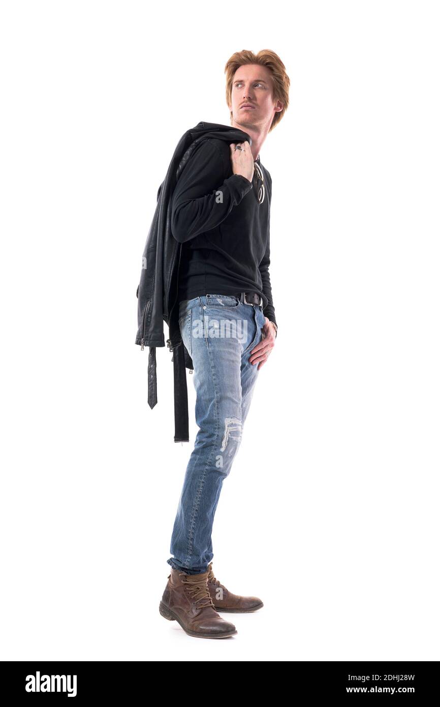 Side view of handsome male fashion model in jeans carrying leather ...