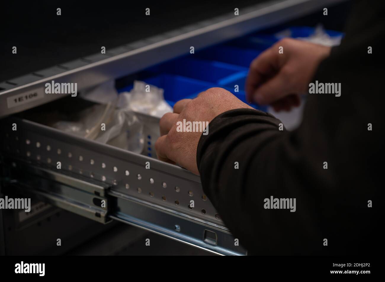 A closeup of a man taking something out from a metal drawer from the ...
