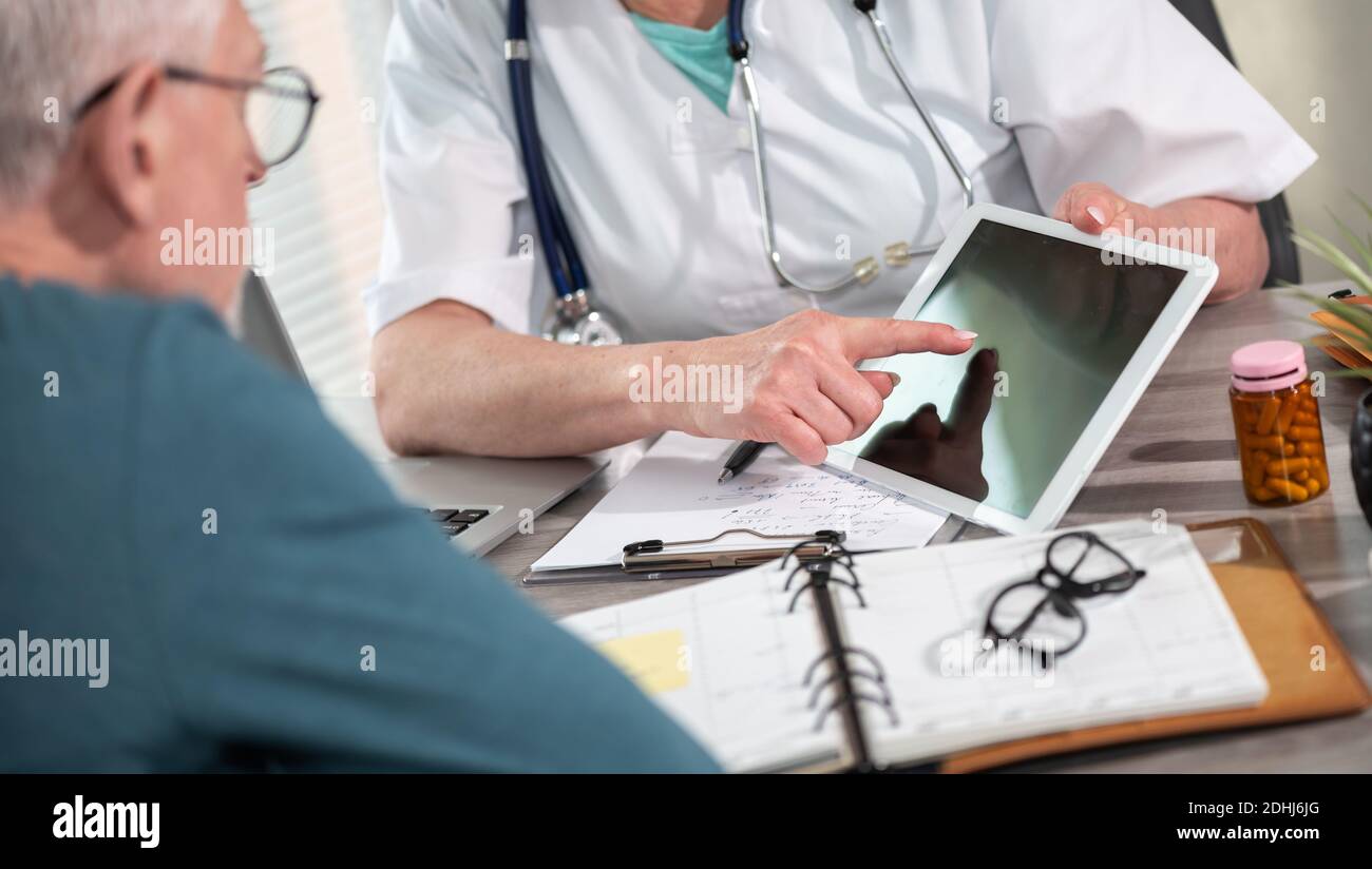 Female doctor showing reports on digital tablet to her patient in ...