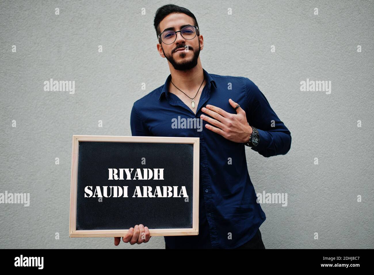 Arab man wear blue shirt and eyeglasses hold board with Riyadh Saudi ...
