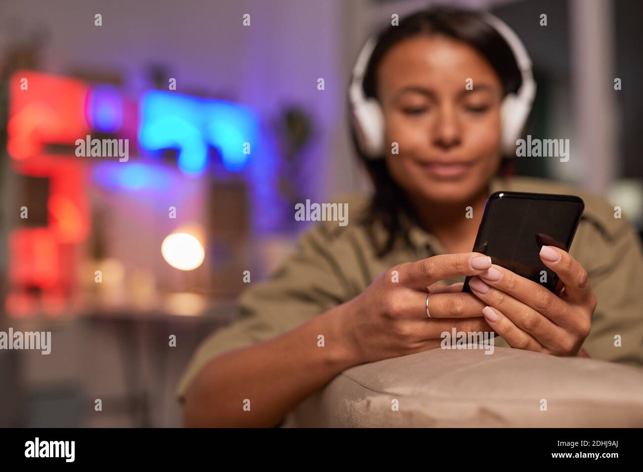 Young woman in headphones typing message on her mobile phone while ...