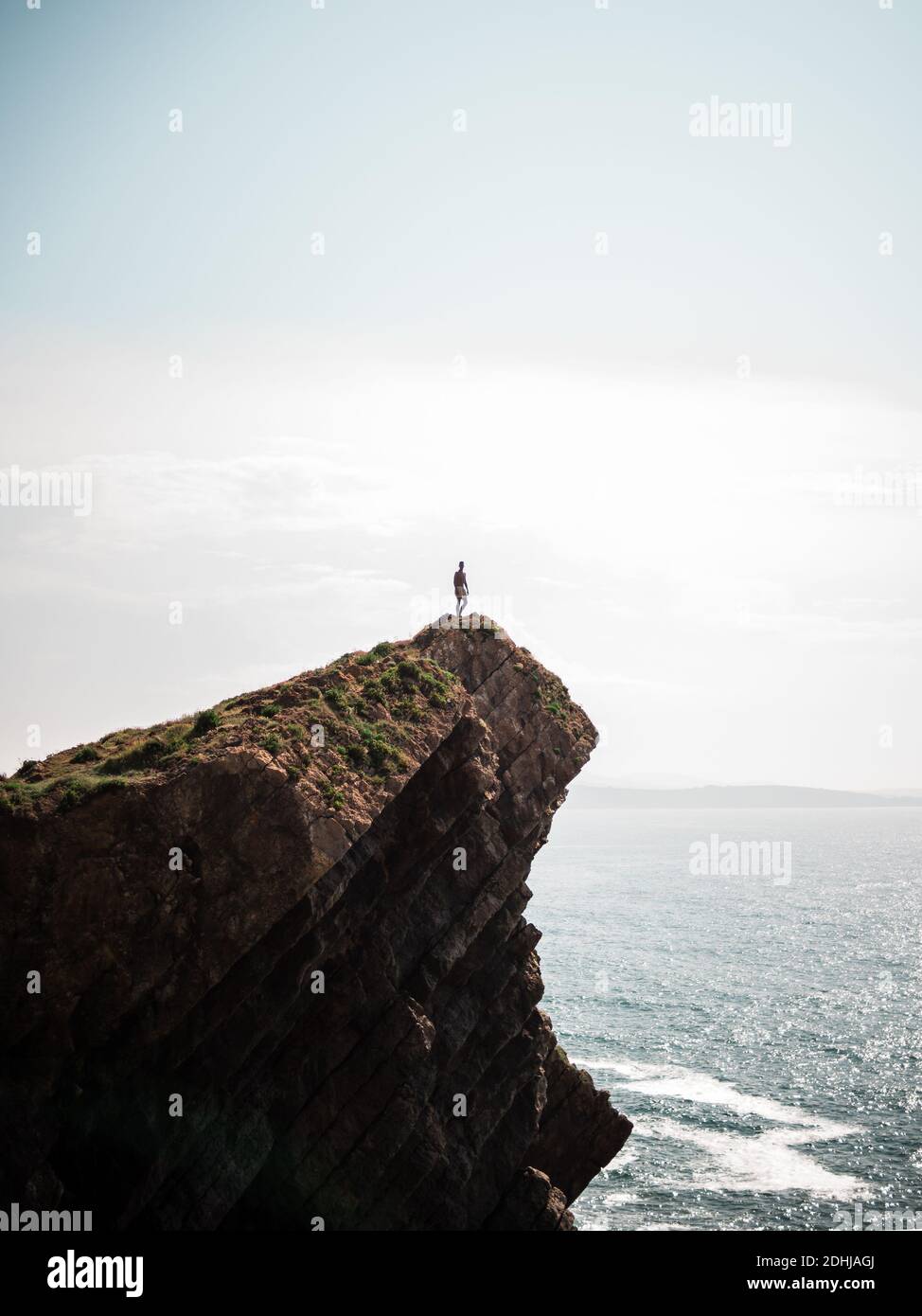 A vertical motivational photograph of a person on top of the cliff ...
