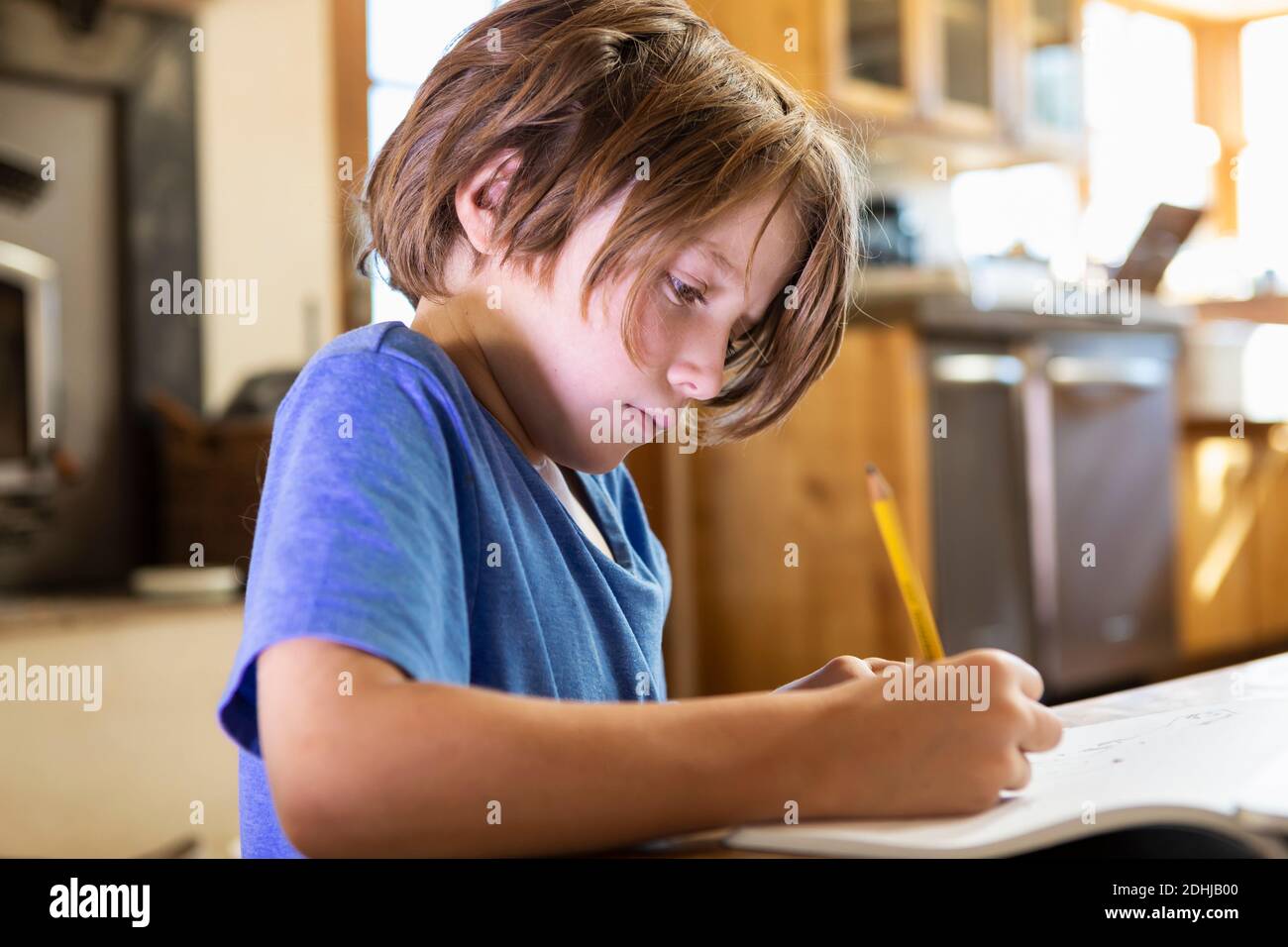 Young boy at home writing and drawing in his drawing pad Stock Photo ...