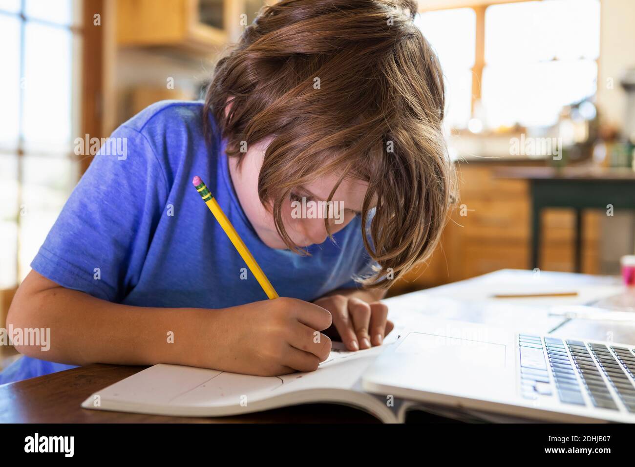 Young boy at home writing and drawing in his drawing pad Stock Photo ...