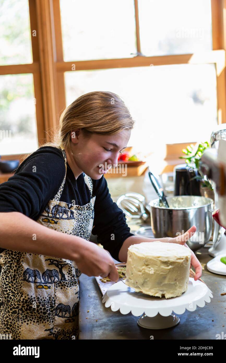teenage girl in kitchen applying icing to cake Stock Photo - Alamy