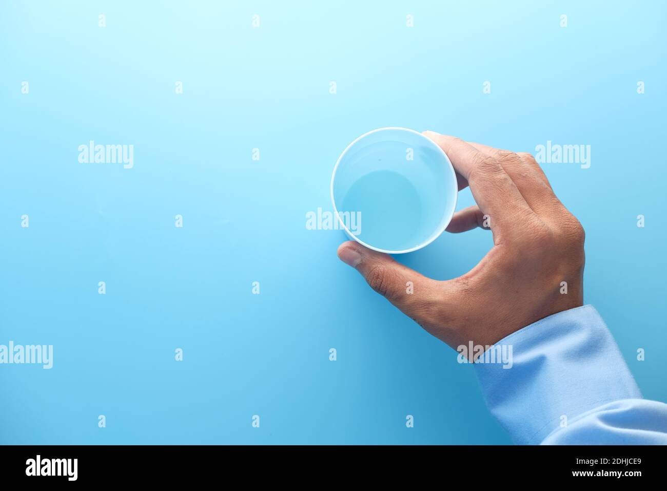 hand holding plastic glass of blue background Stock Photo - Alamy
