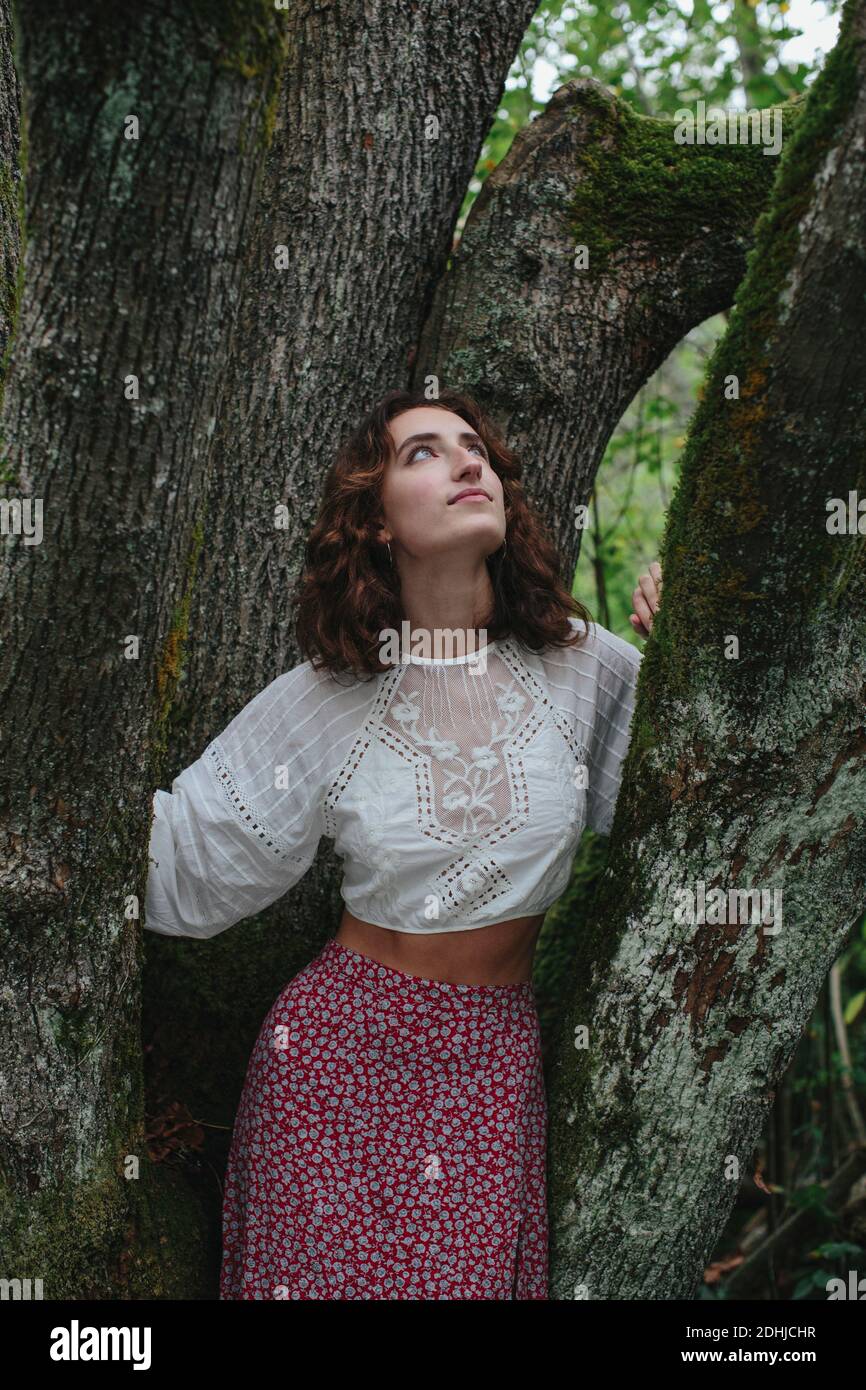 Portrait of seventeen year old girl standing in front of mossy Bigleaf ...