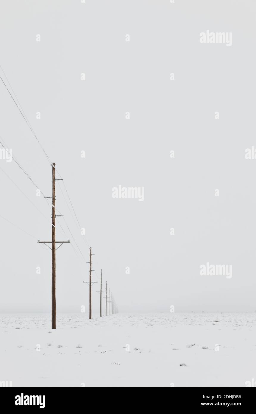 Power lines in snowy wintry landscape with grey sky Stock Photo - Alamy