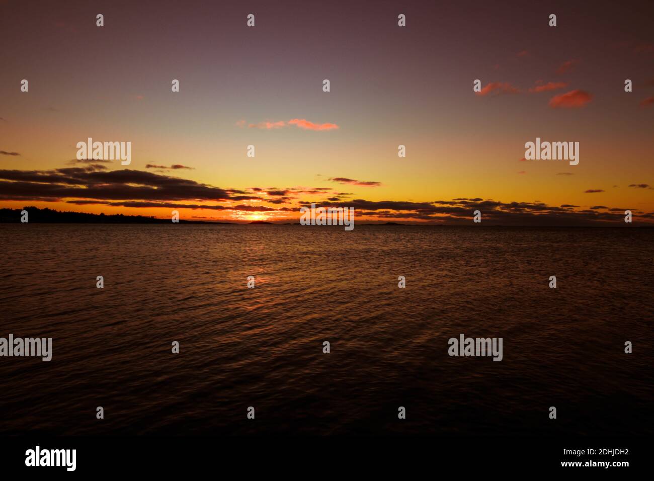 A beautiful setting down sunset sun on the horizon and a calm waveless ...