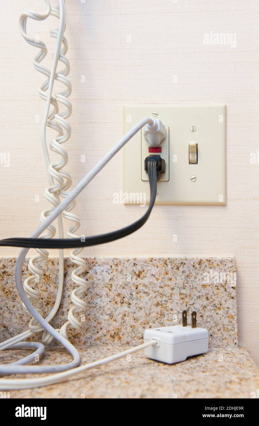 Cords plugged into electrical socket or outlet and telephone cable ...