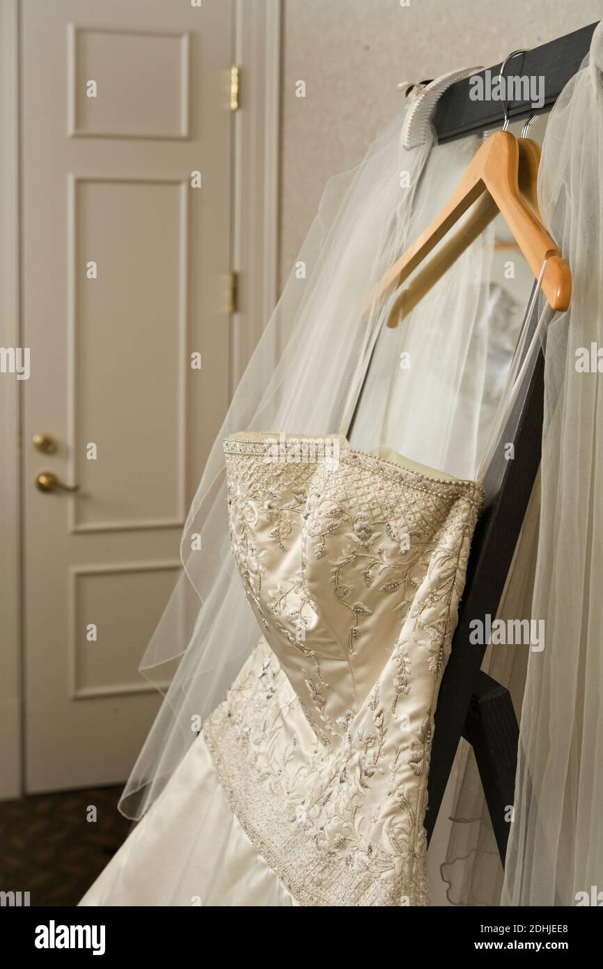 Wedding dress and veil hanging on rack in hotel room Stock Photo - Alamy