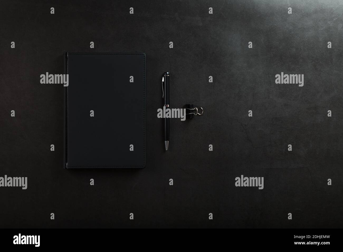 Black Notepad with a black pen on a black background. Top view ...