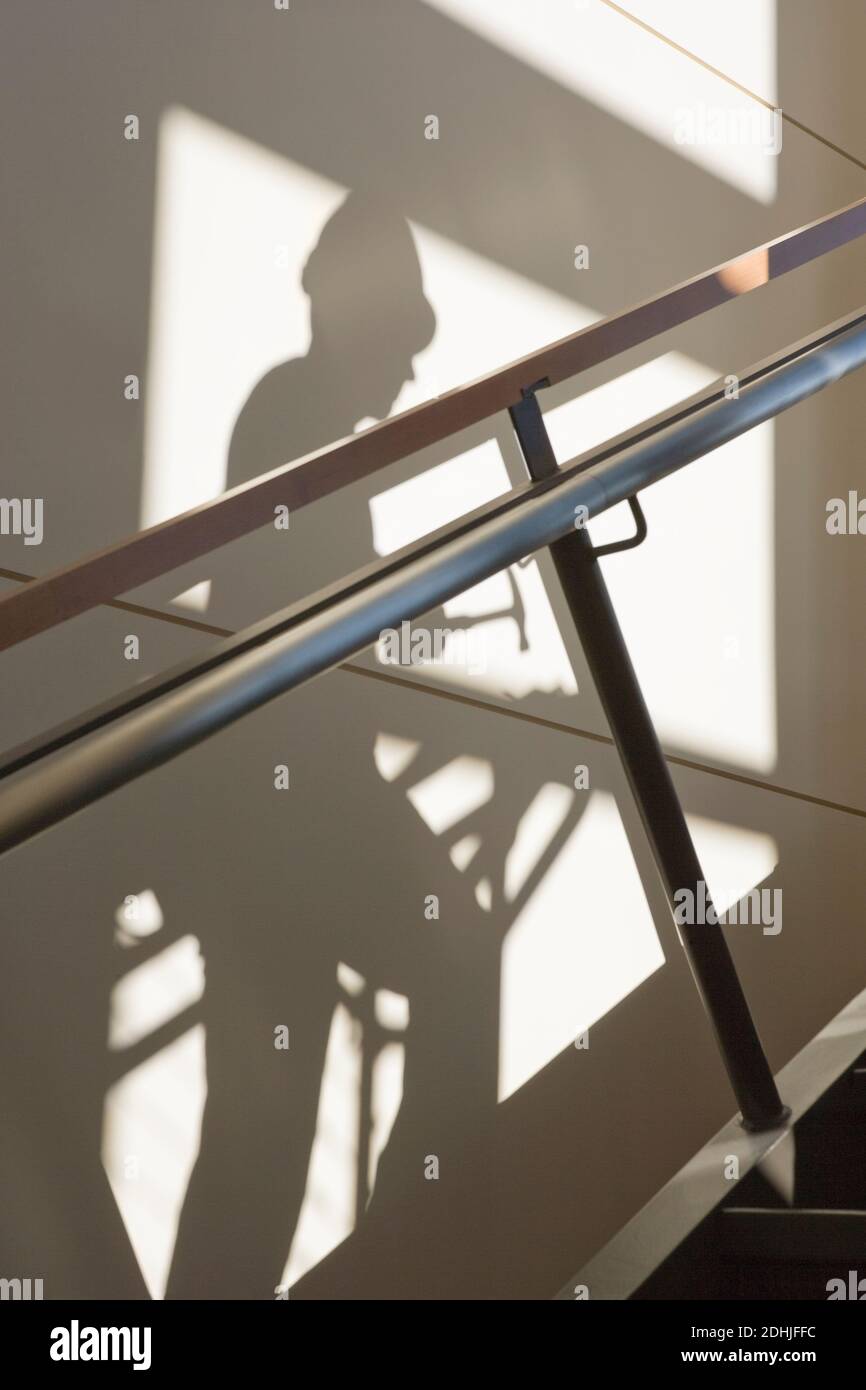 Shadow of a construction worker walking up stairs on wall with handrail ...
