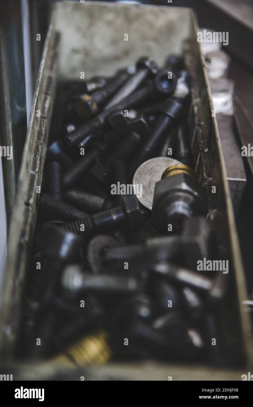 A vertical closeup shot of a pile of black tempered bolts in a metal ...