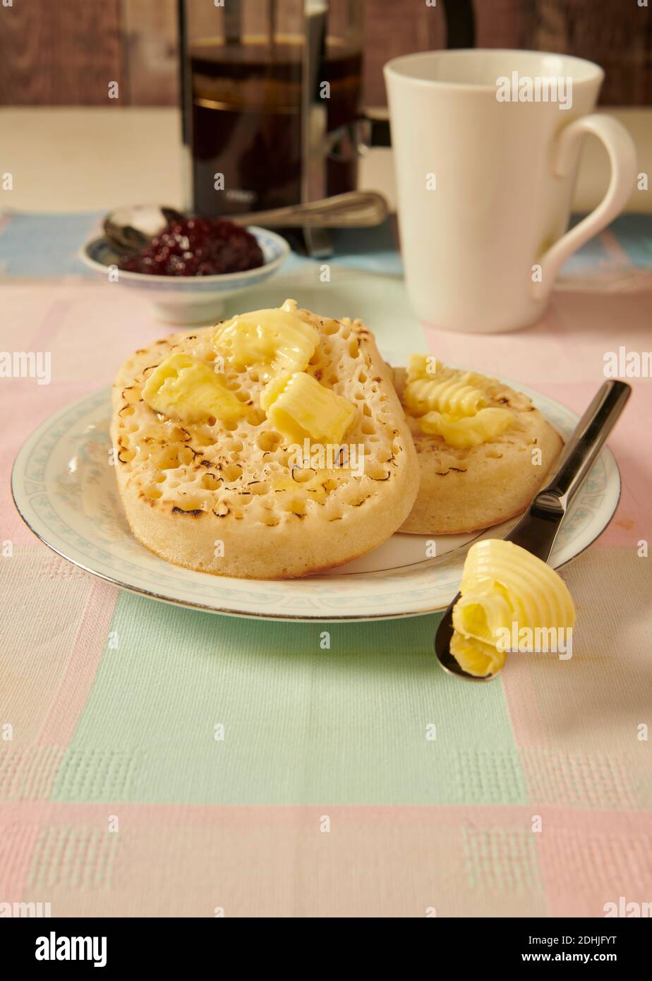 Traditional hot buttered toasted crumpets on a white plate on a table ...