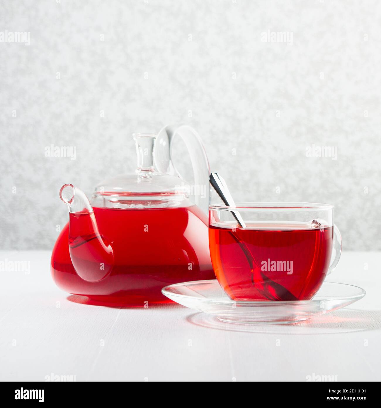 Red tea in elegant transparent teapot with cup in sunlight on white ...