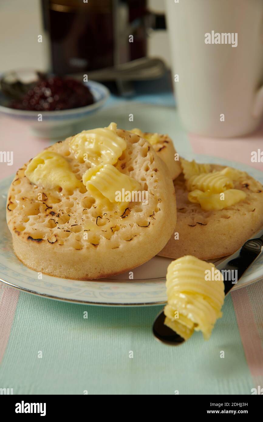 Traditional hot buttered toasted crumpets on a white plate on a table ...