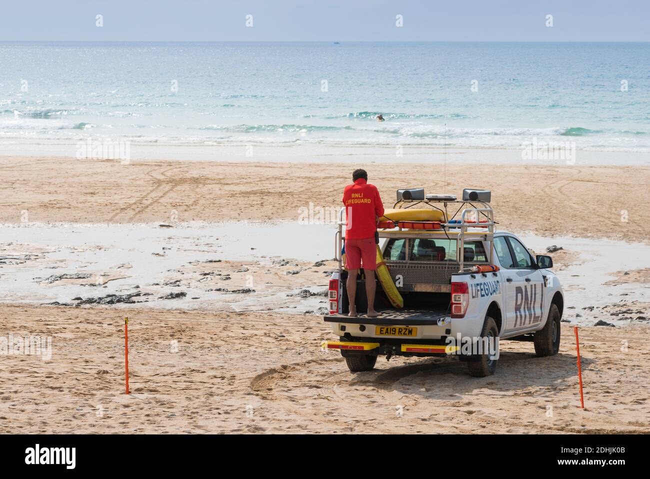 A RNLI Lifeguard on duty standing on the back of an emergency response ...