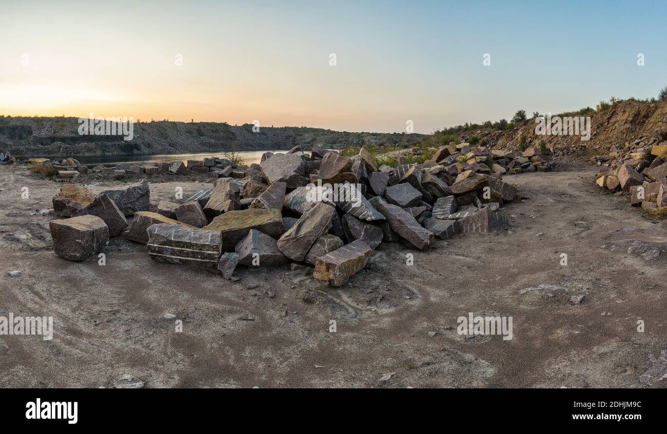 There are large piles of boulders in the warm evening light on the ...