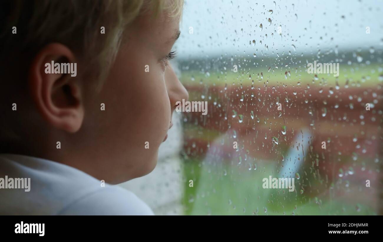 A little boy looks out the window during the rain Stock Photo - Alamy