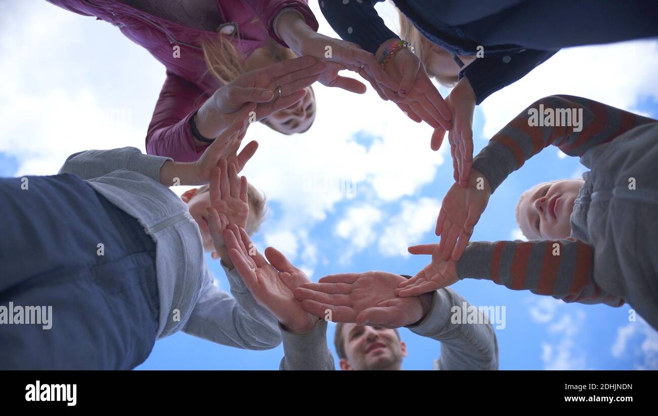 A friendly family makes a circle out of their hands against the blue ...