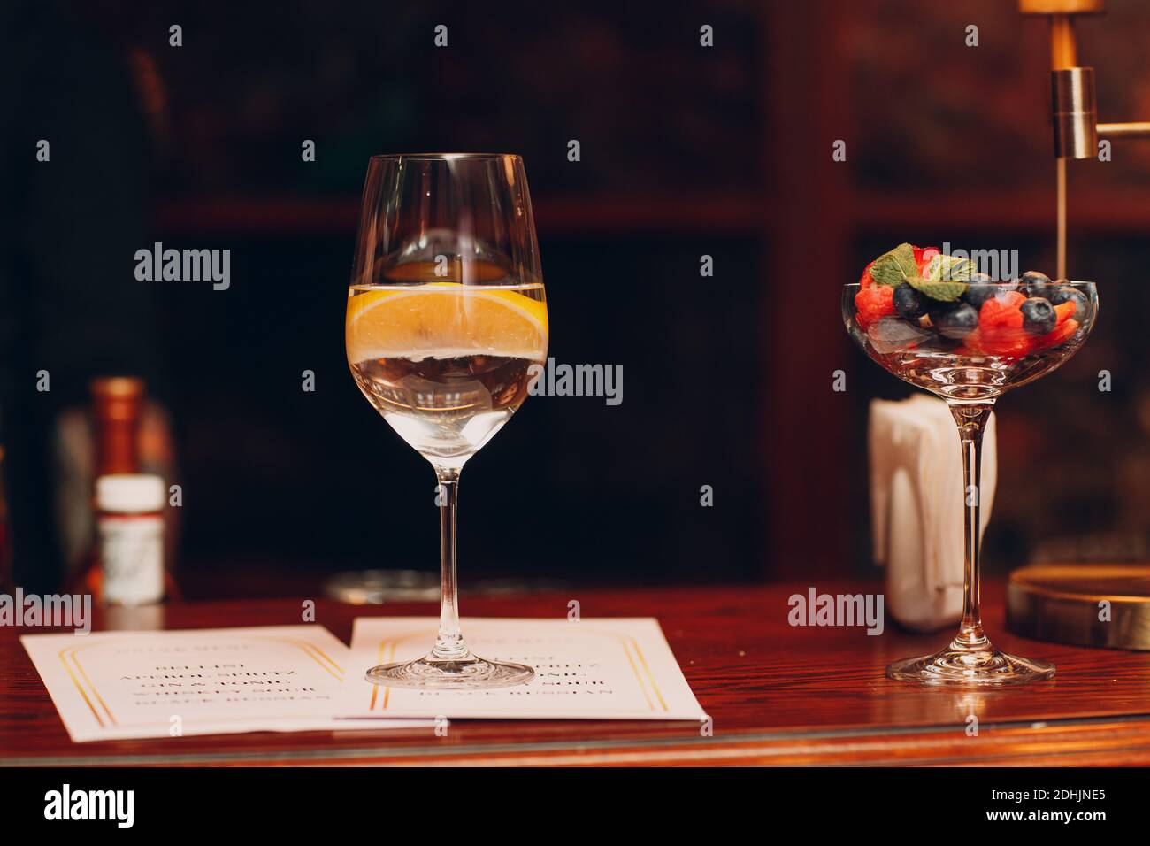 Cocktail with lemon in glass on bar desk with menu Stock Photo - Alamy