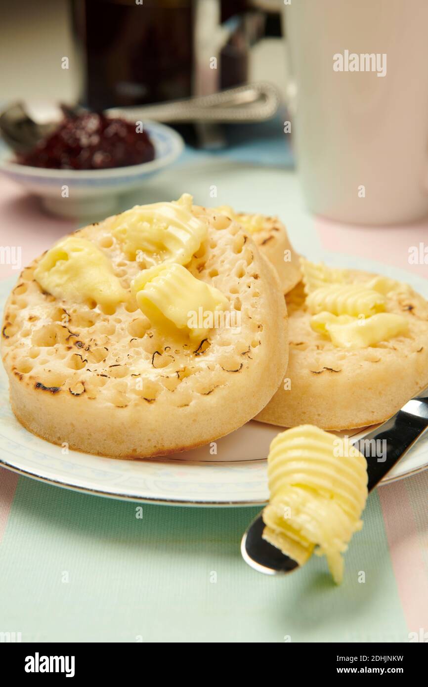 Traditional hot buttered toasted crumpets on a white plate on a table ...