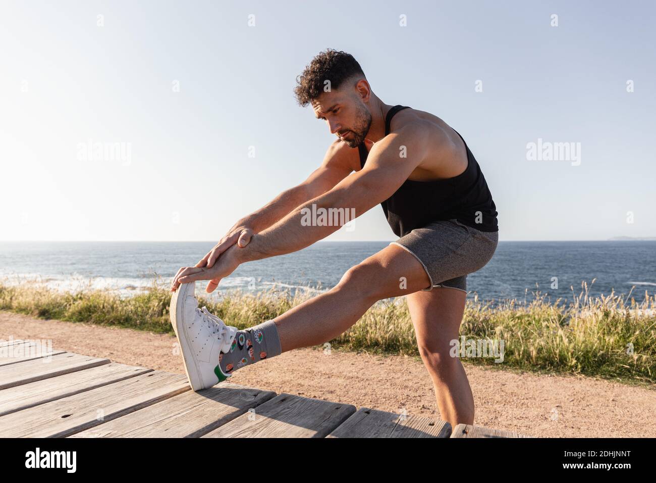 Side view of muscular male doing forward bends and warming up before ...