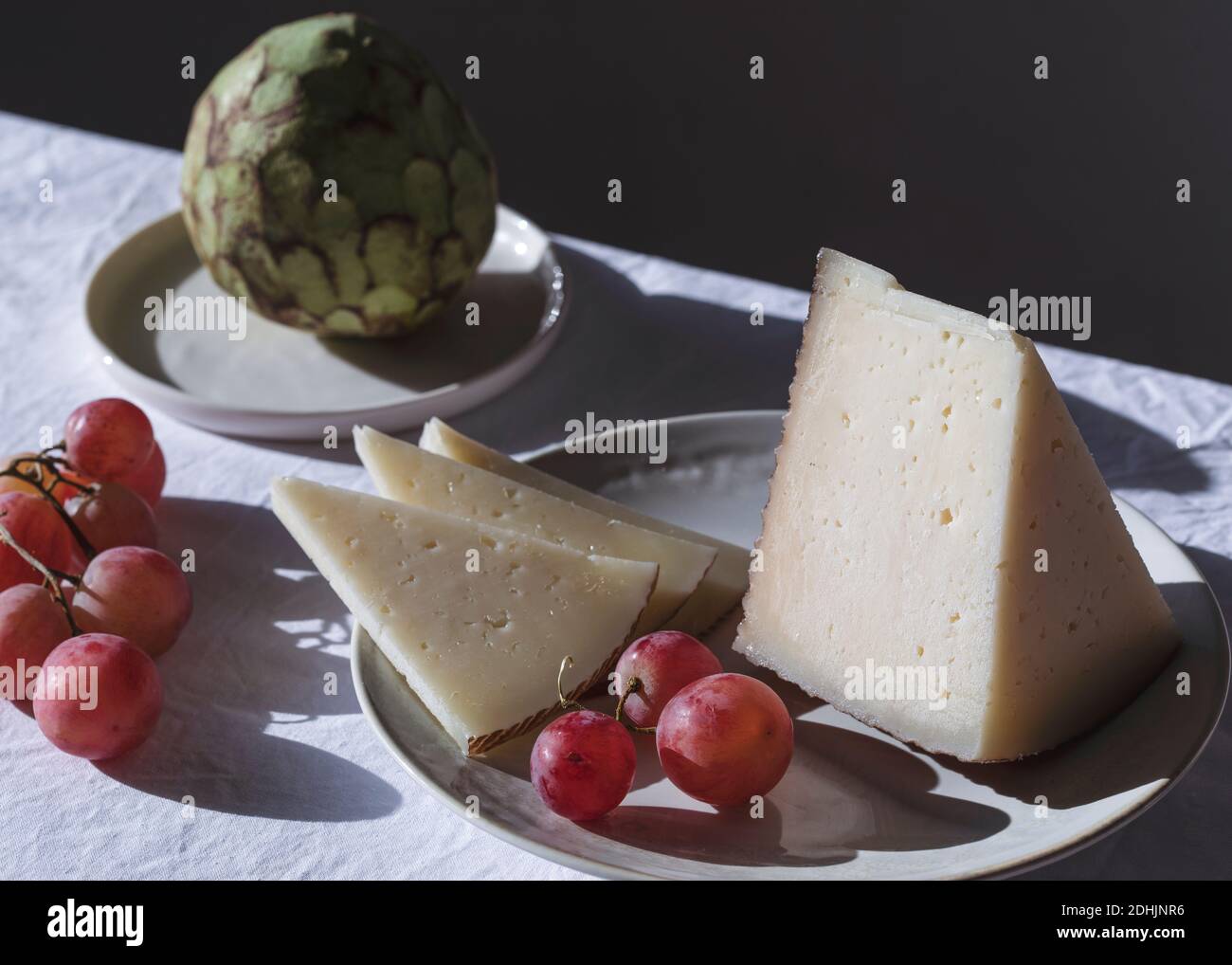 Table with sweet fruits and delectable cheese in bright room lit by ...